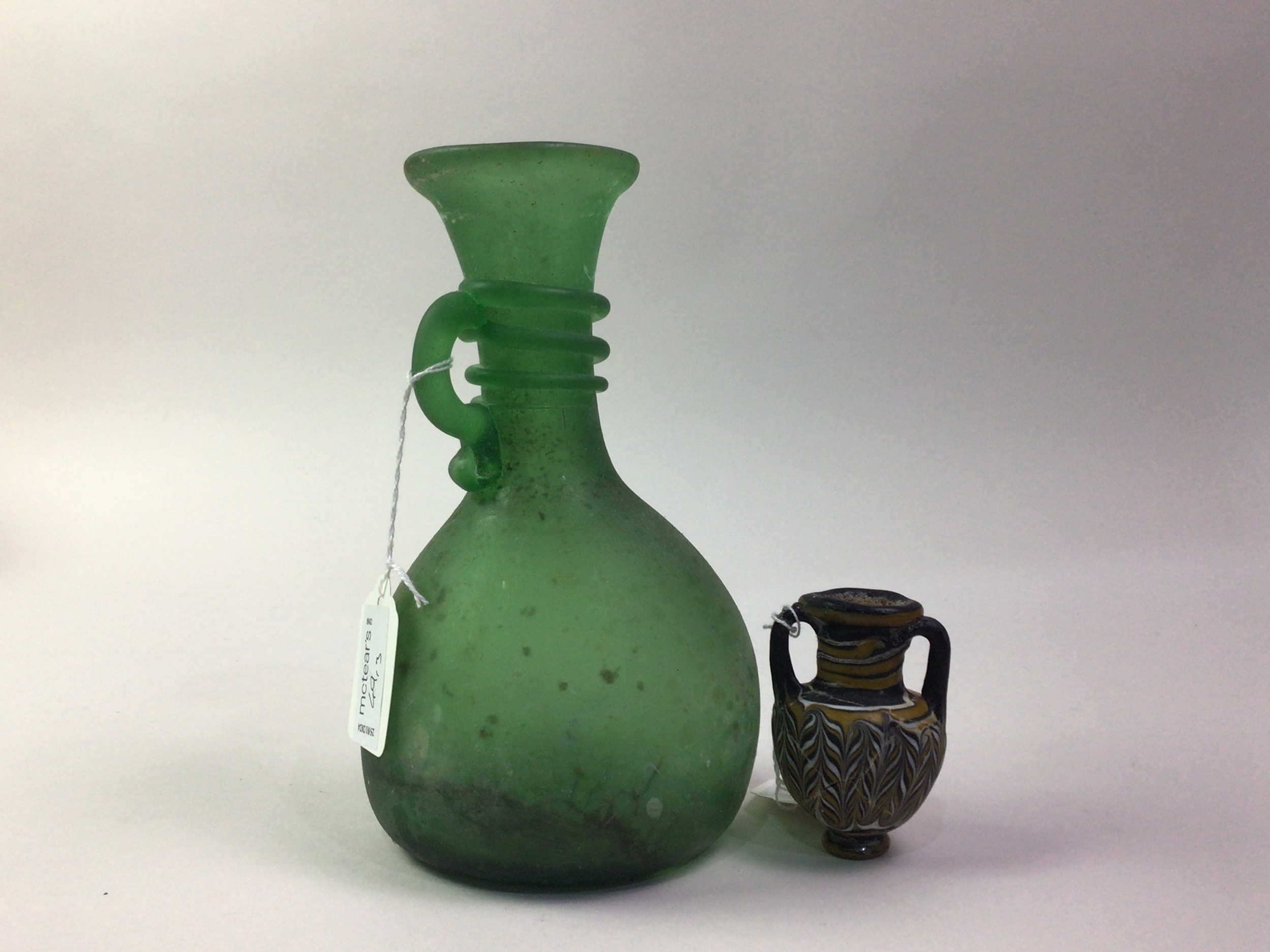 Lot 49 - TWO MINIATURE GREEK CORE FORMED GLASS VESSELS,